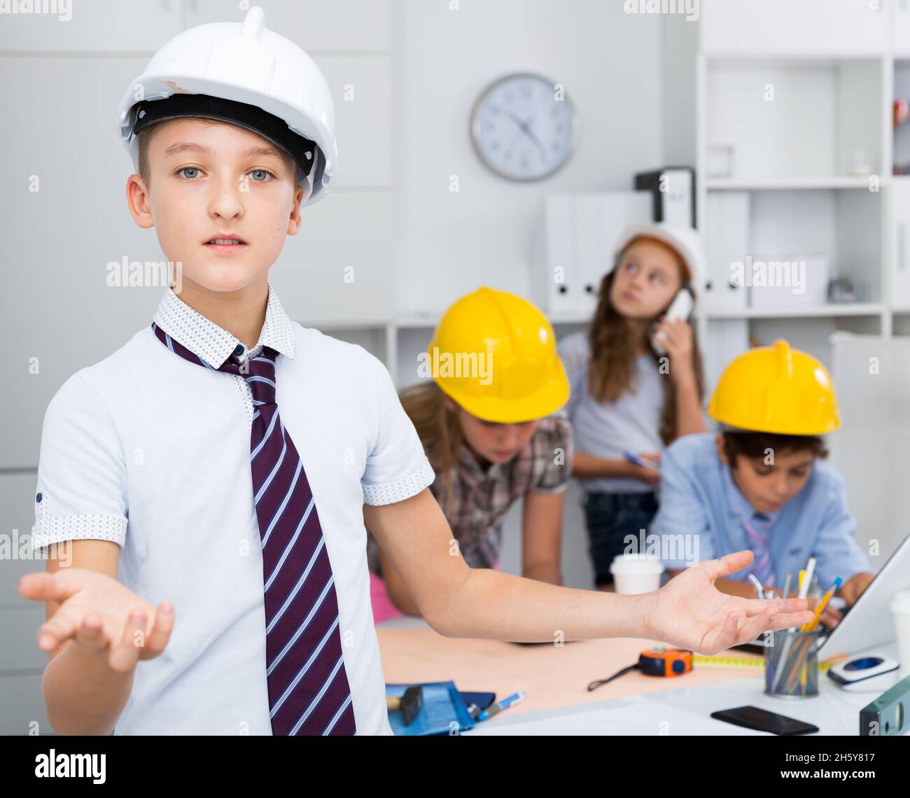 Teenager boy engineer and children with plan Stock Photo - Alamy