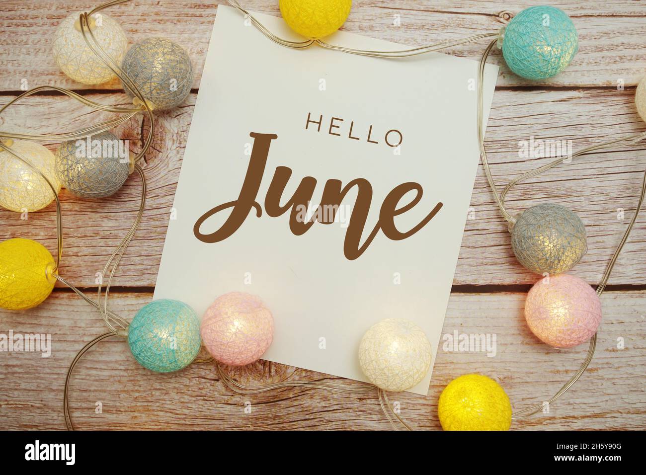 Hello June card typography text with LED cotton ball on wooden ...