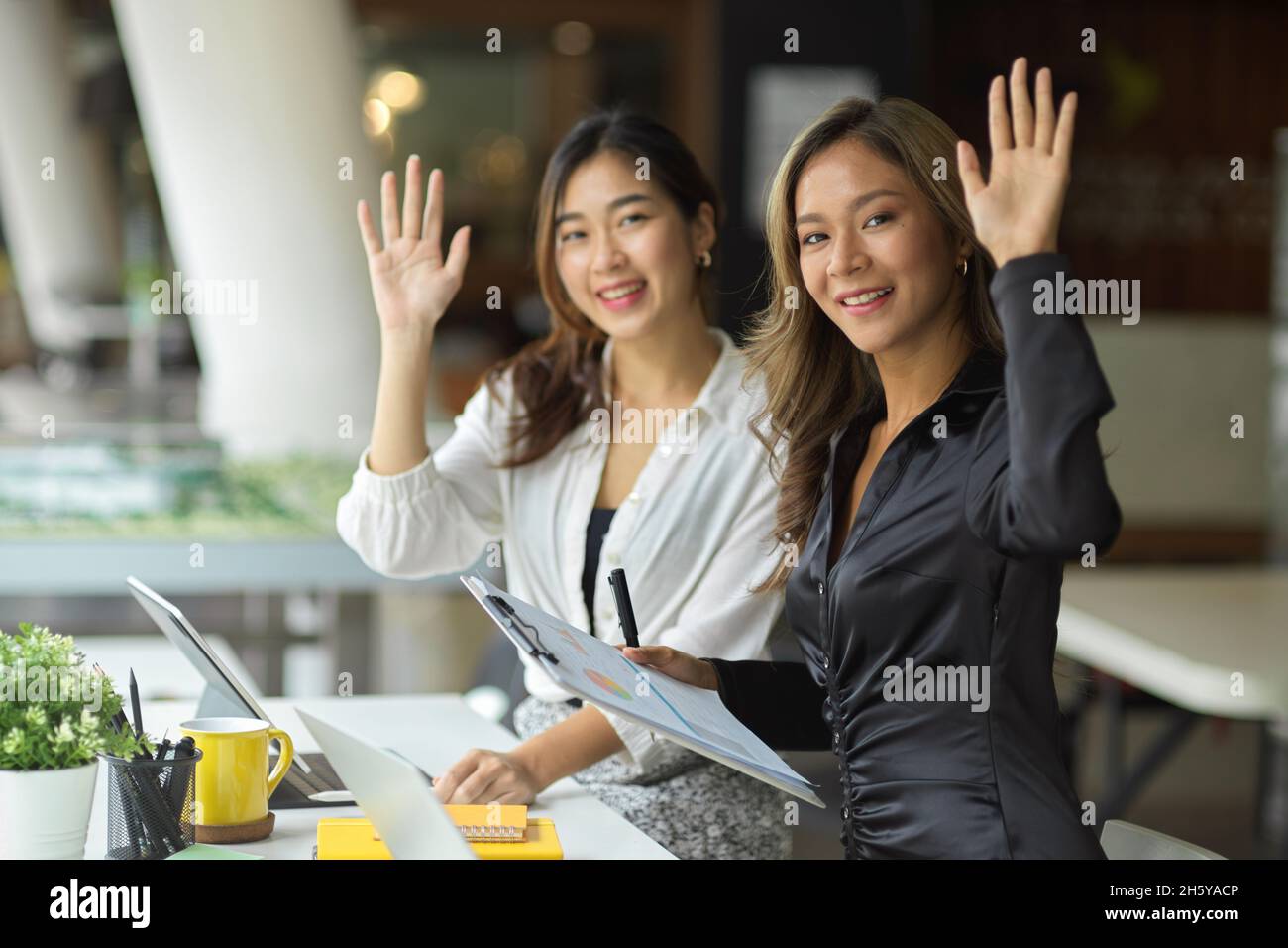 Beautiful and cheerful businesswomen raising hand palm up, hand ...
