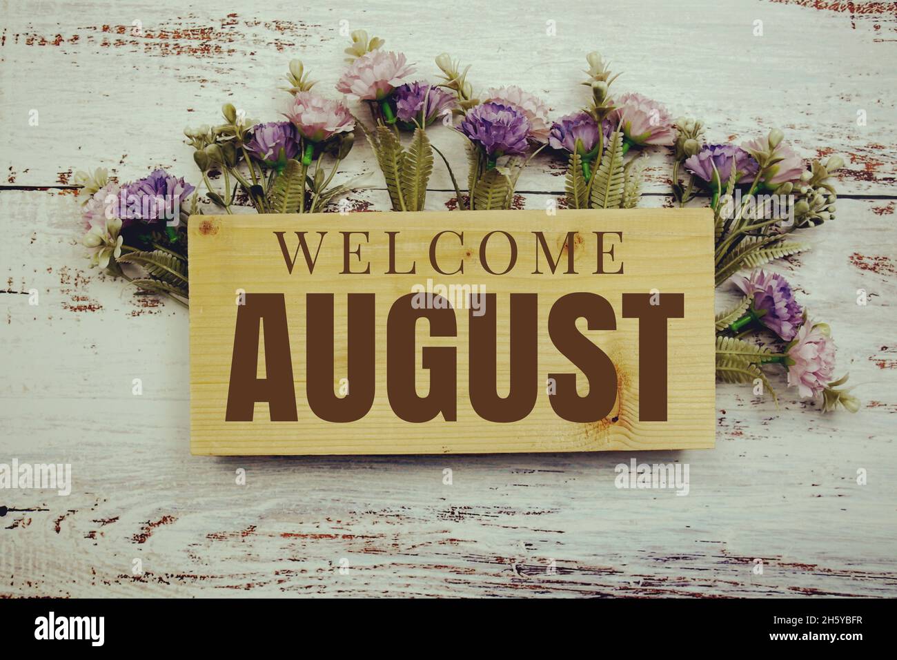 Welcome August text on wooden board with flowers frame on wooden ...