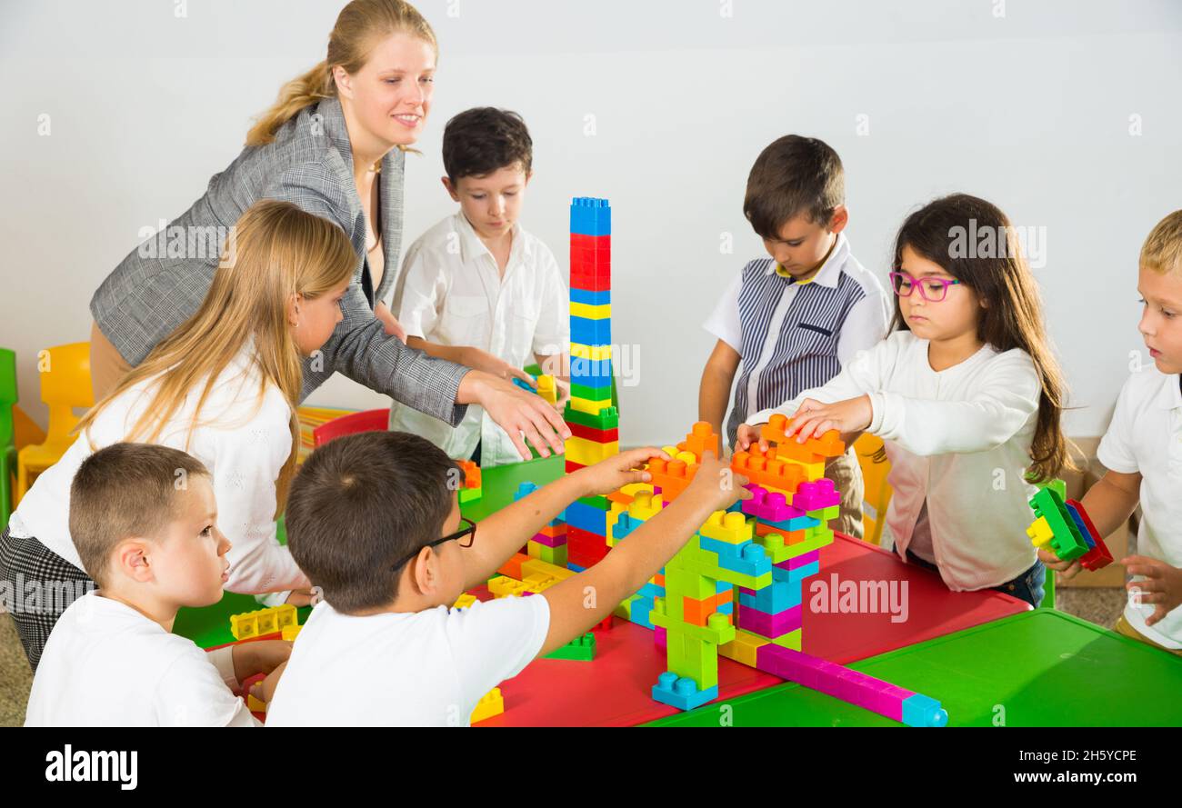 Teacher and happy schoolkids playing building blocks Stock Photo - Alamy