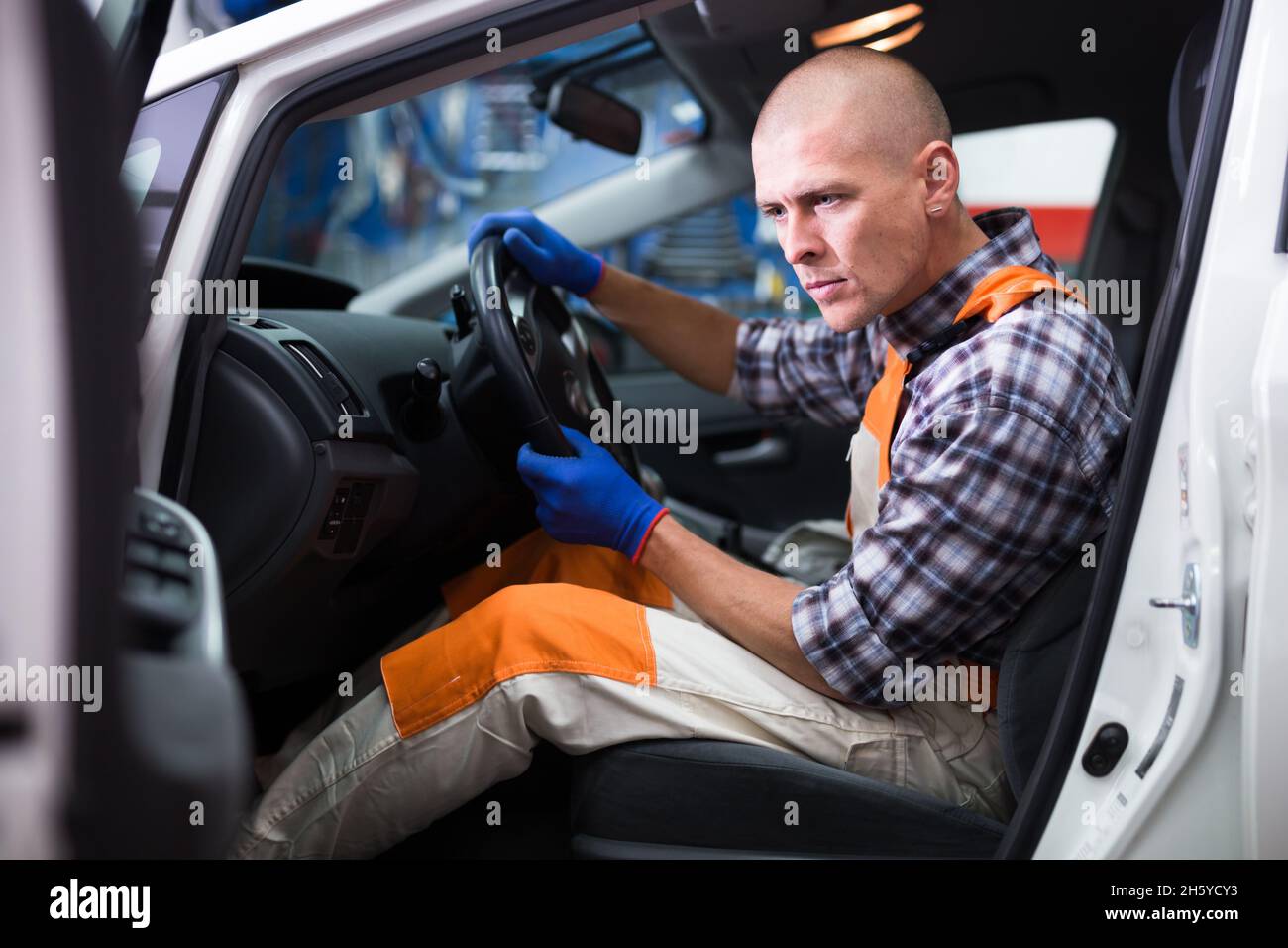 Auto mechanic sitting in broken car and listens to engine operation ...