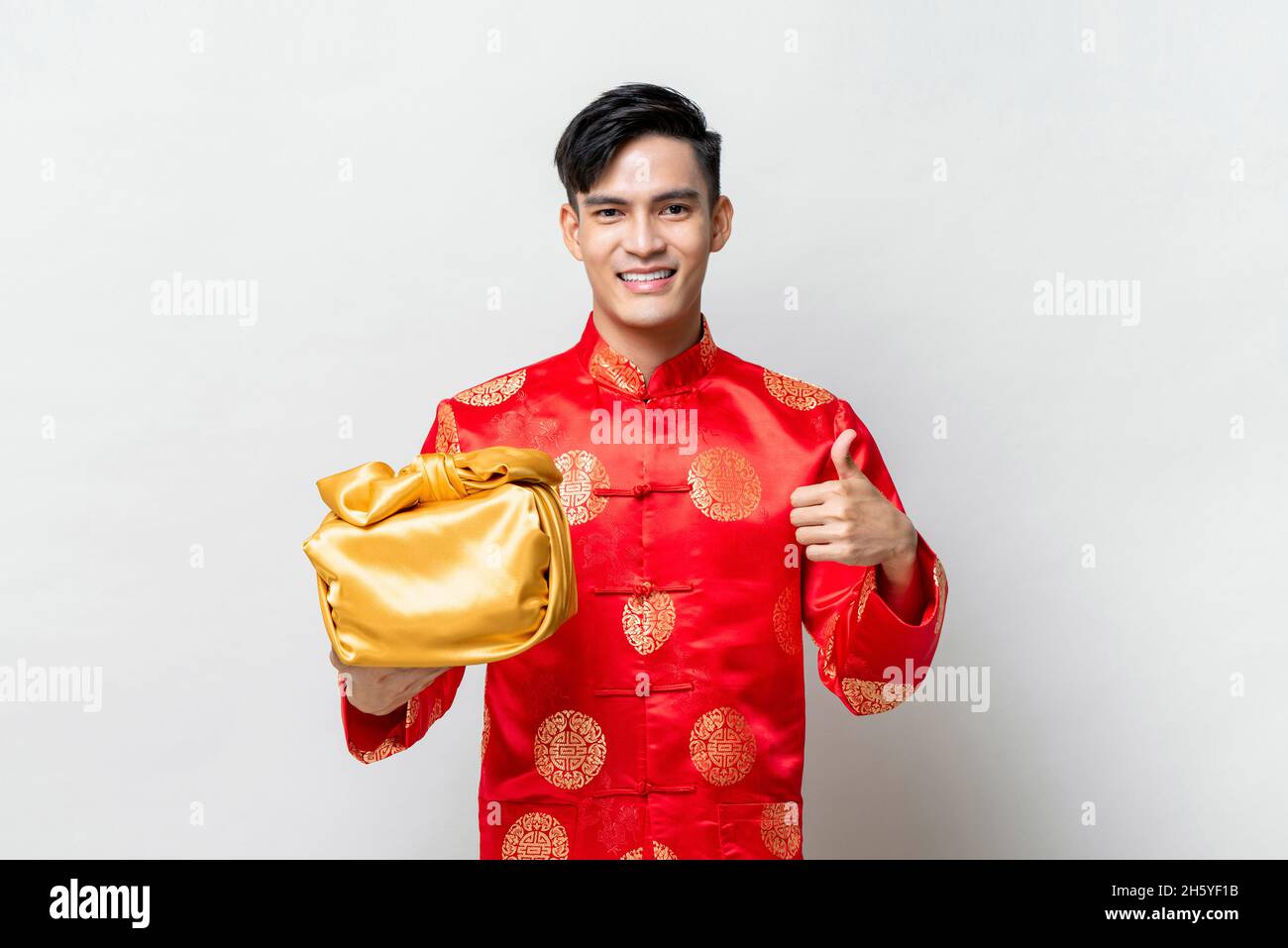 Happy smiling Asian man in traditional costume giving gold gift box in ...