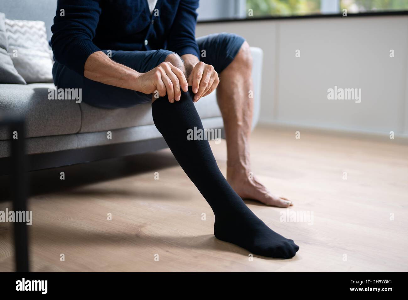 Man Putting On Medical Compression Stockings On Legs Stock Photo - Alamy