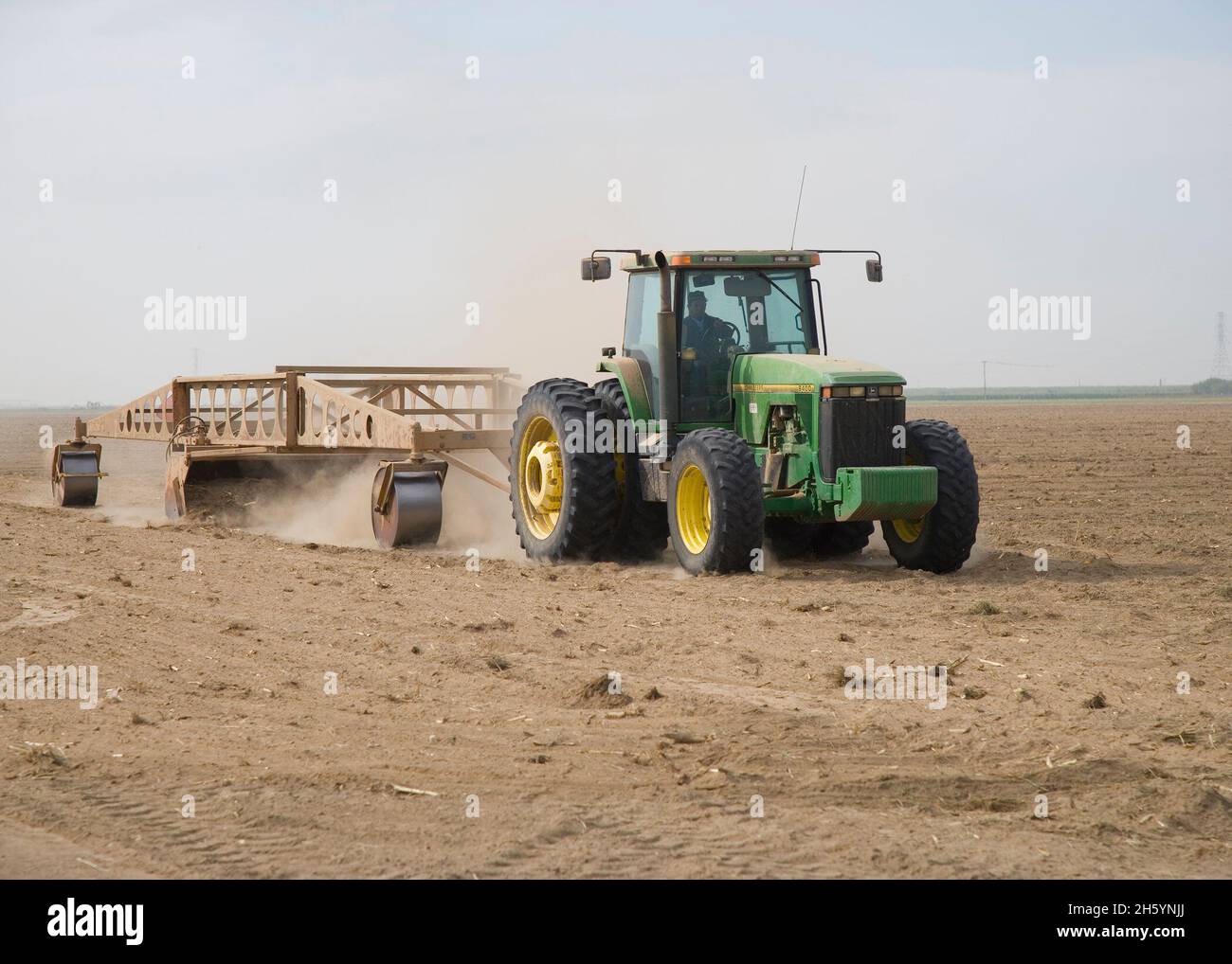 Farmer in his John Deere tractor in a dusty field ca. 2011 or earlier ...