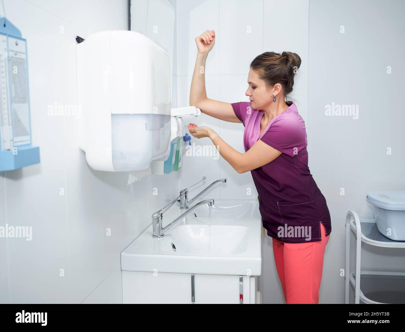 A female doctor applies an antiseptic soap to her hands from a ...