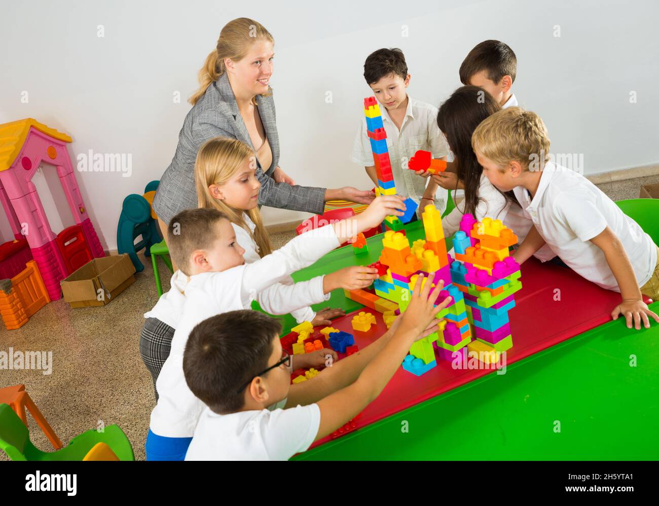 Teacher and happy schoolkids playing building blocks Stock Photo - Alamy