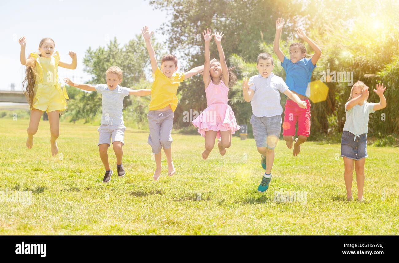 Schoolchildren jumping and smiling together in park Stock Photo - Alamy