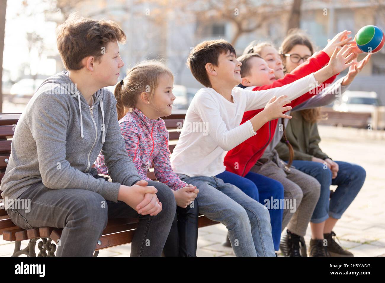 Children sitting on bench and playing ball Stock Photo - Alamy