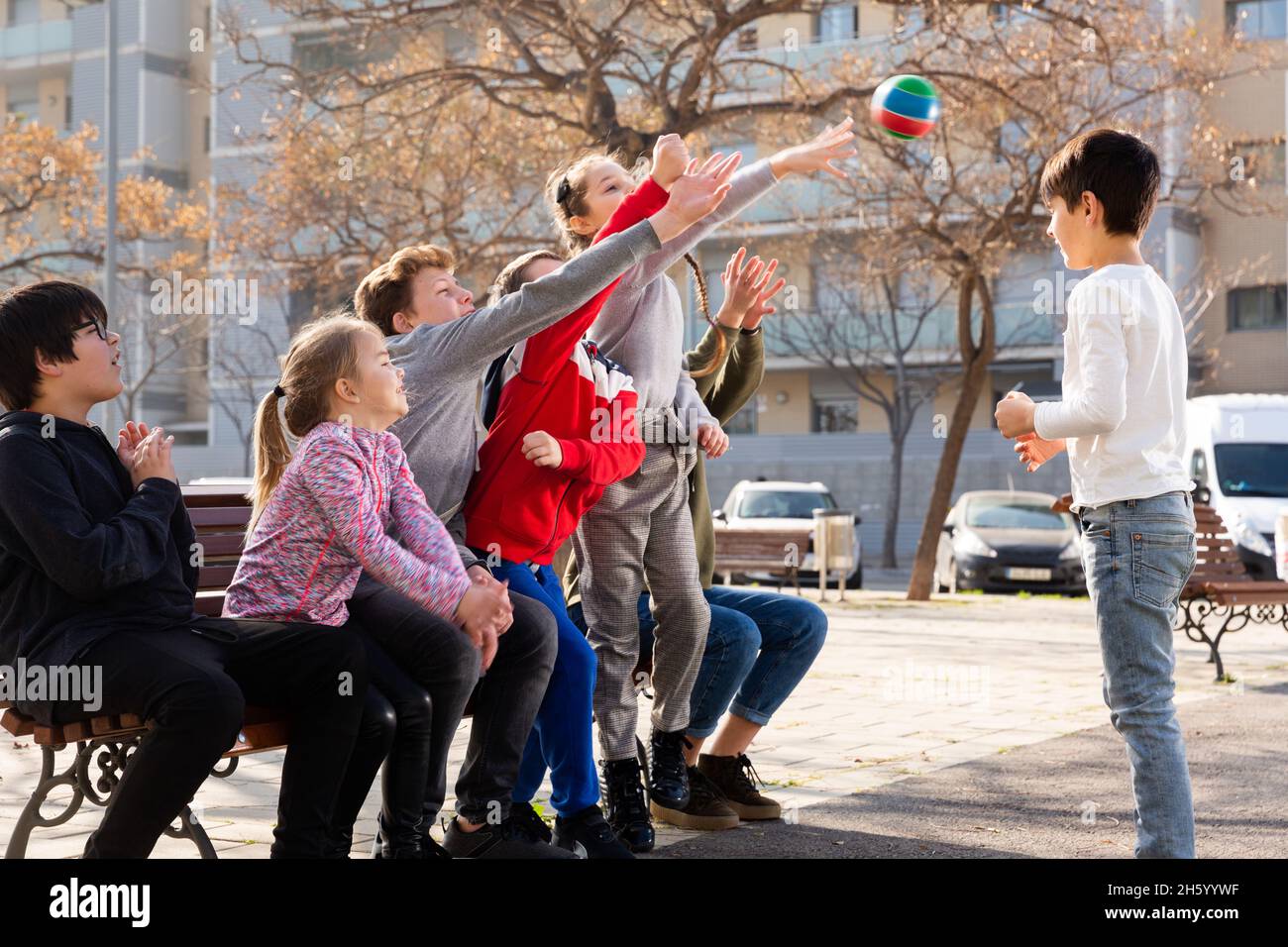 Children sitting on bench and playing ball Stock Photo - Alamy