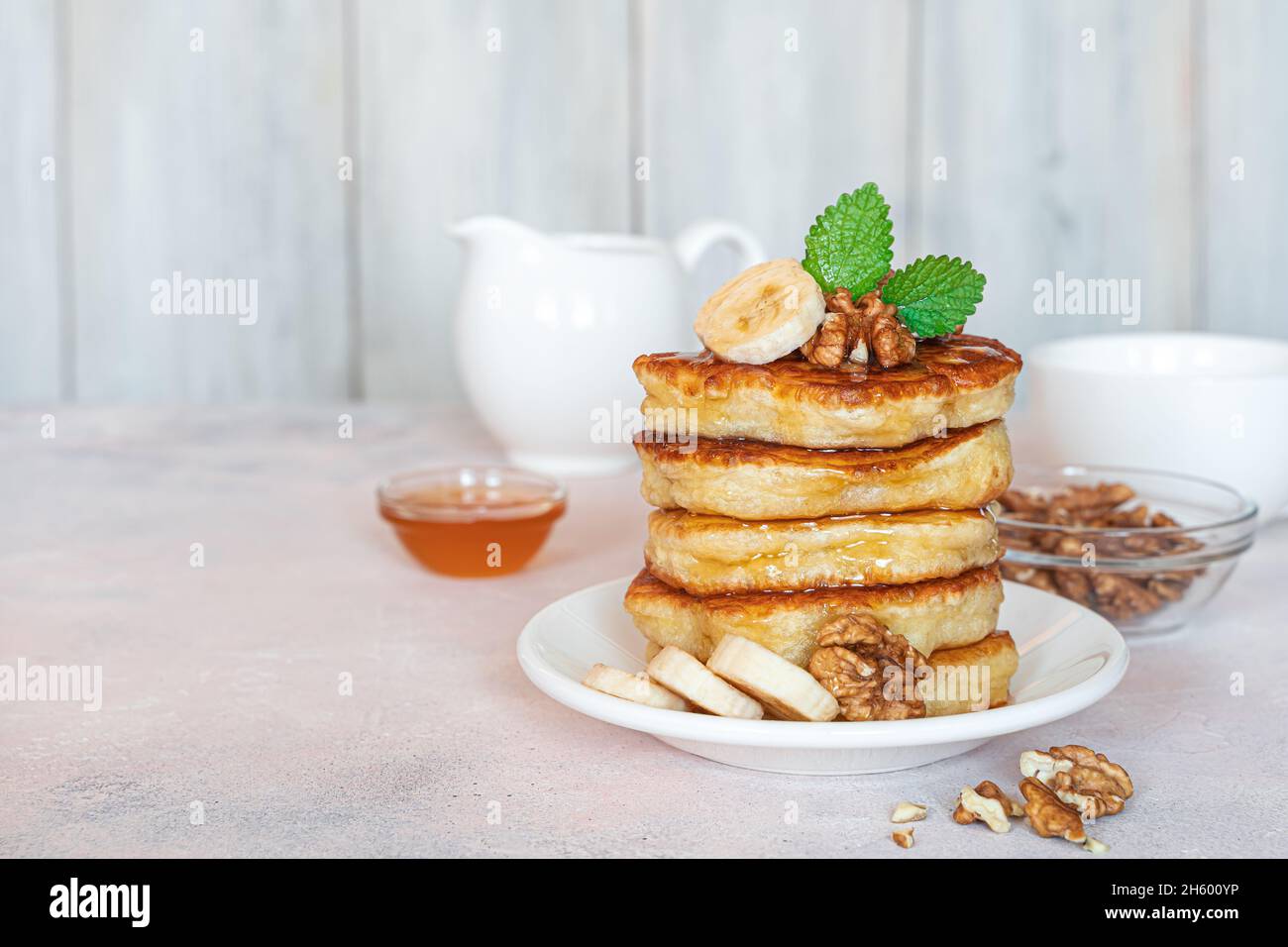 Breakfast with pancakes with honey and nuts on a light background. Side ...