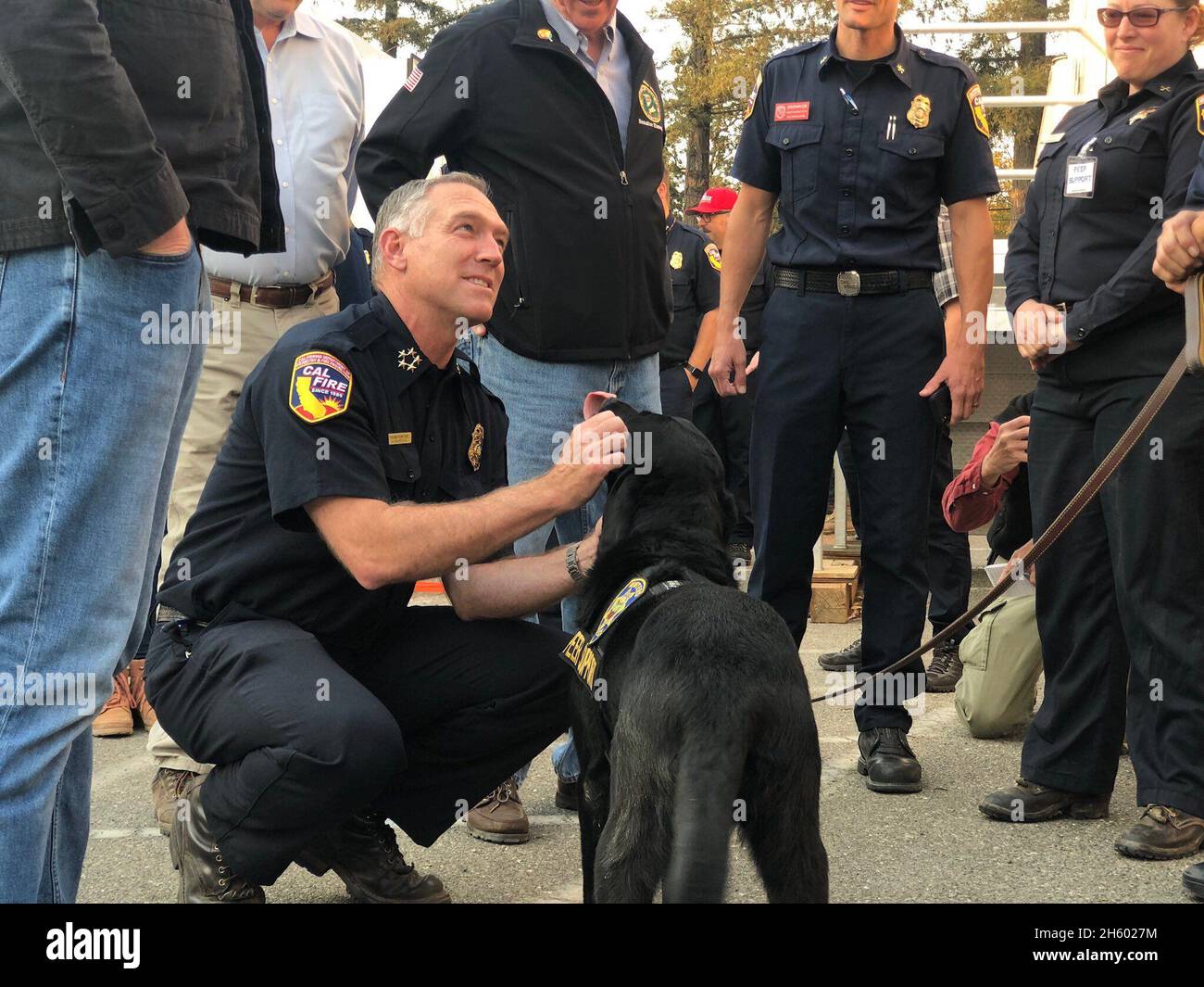 CAL FIRE team member pets a dog at the Kincade Fire base camp ca. 28 ...