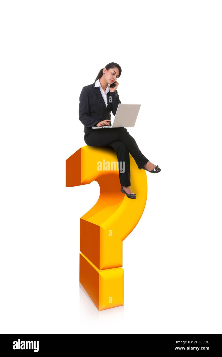 A female employee in business suit working on laptop while talking on ...