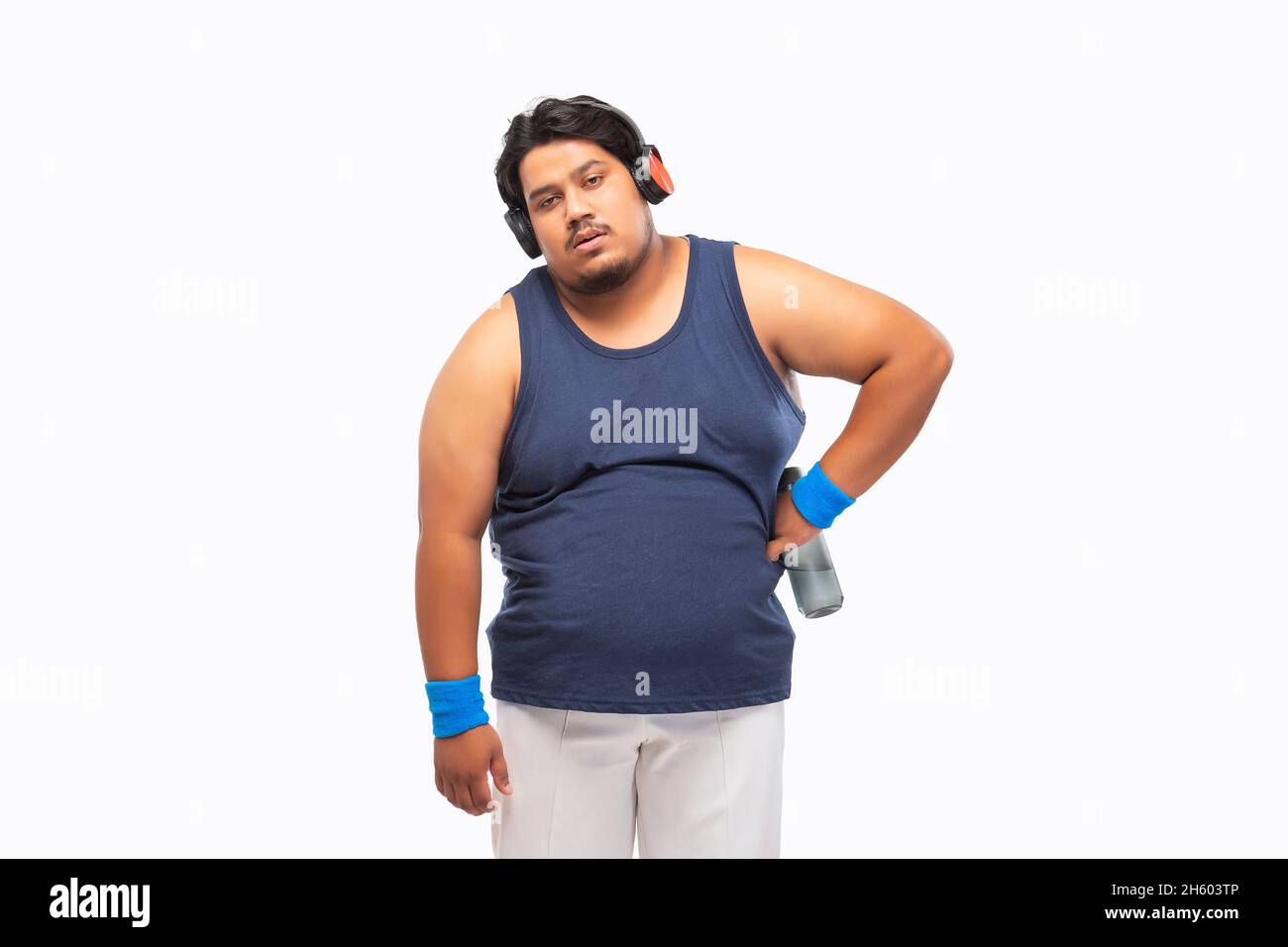 Portait of a fat man standing with headphones around neck exhausted ...