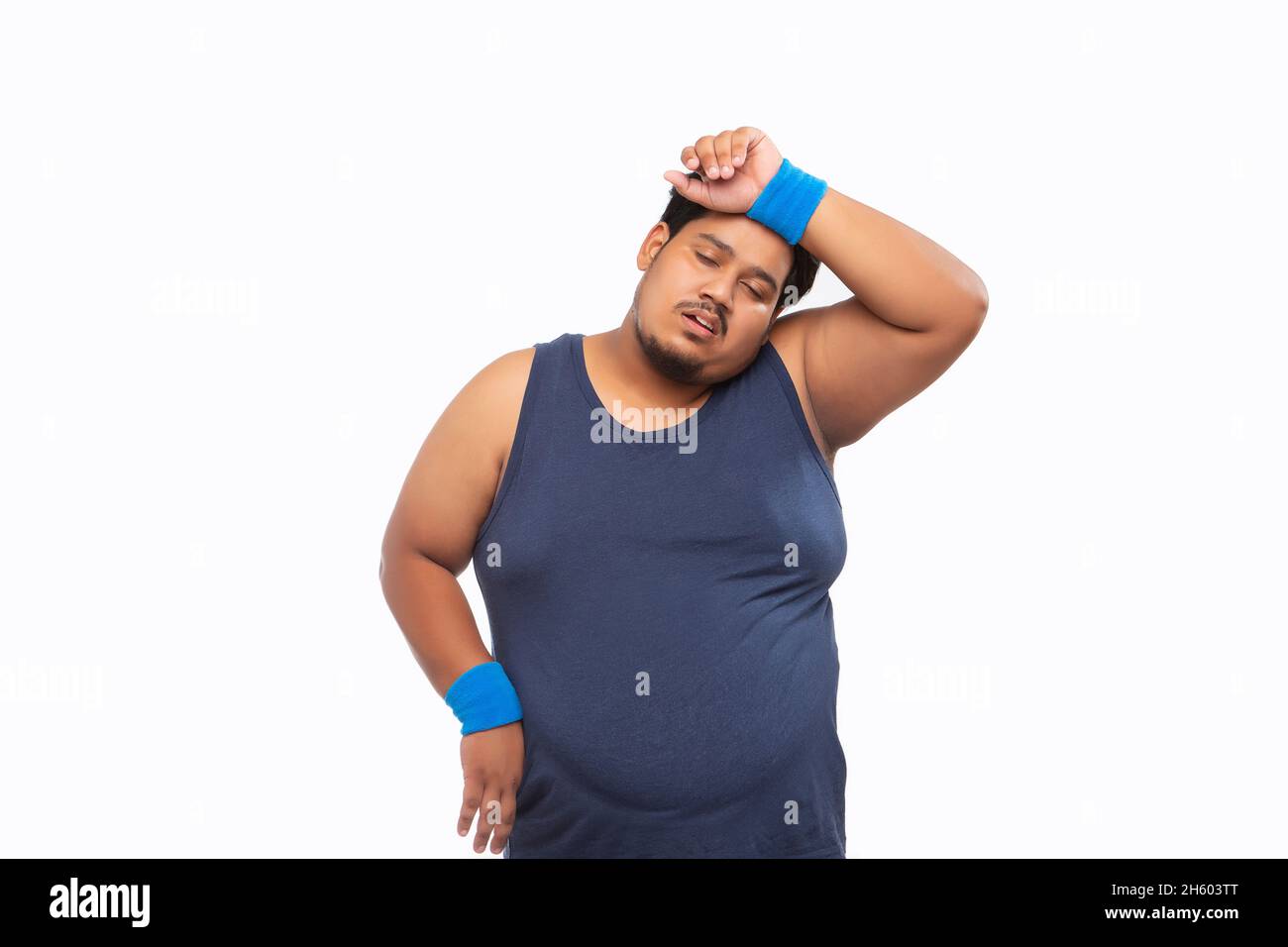 Portait of a fat man standing exhausted after a workout against plain ...