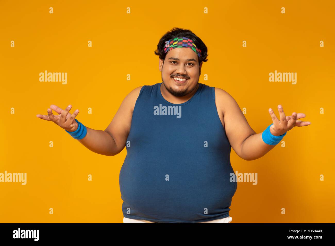 Portrait of a fat man smiling and shrugging with hands against plain ...