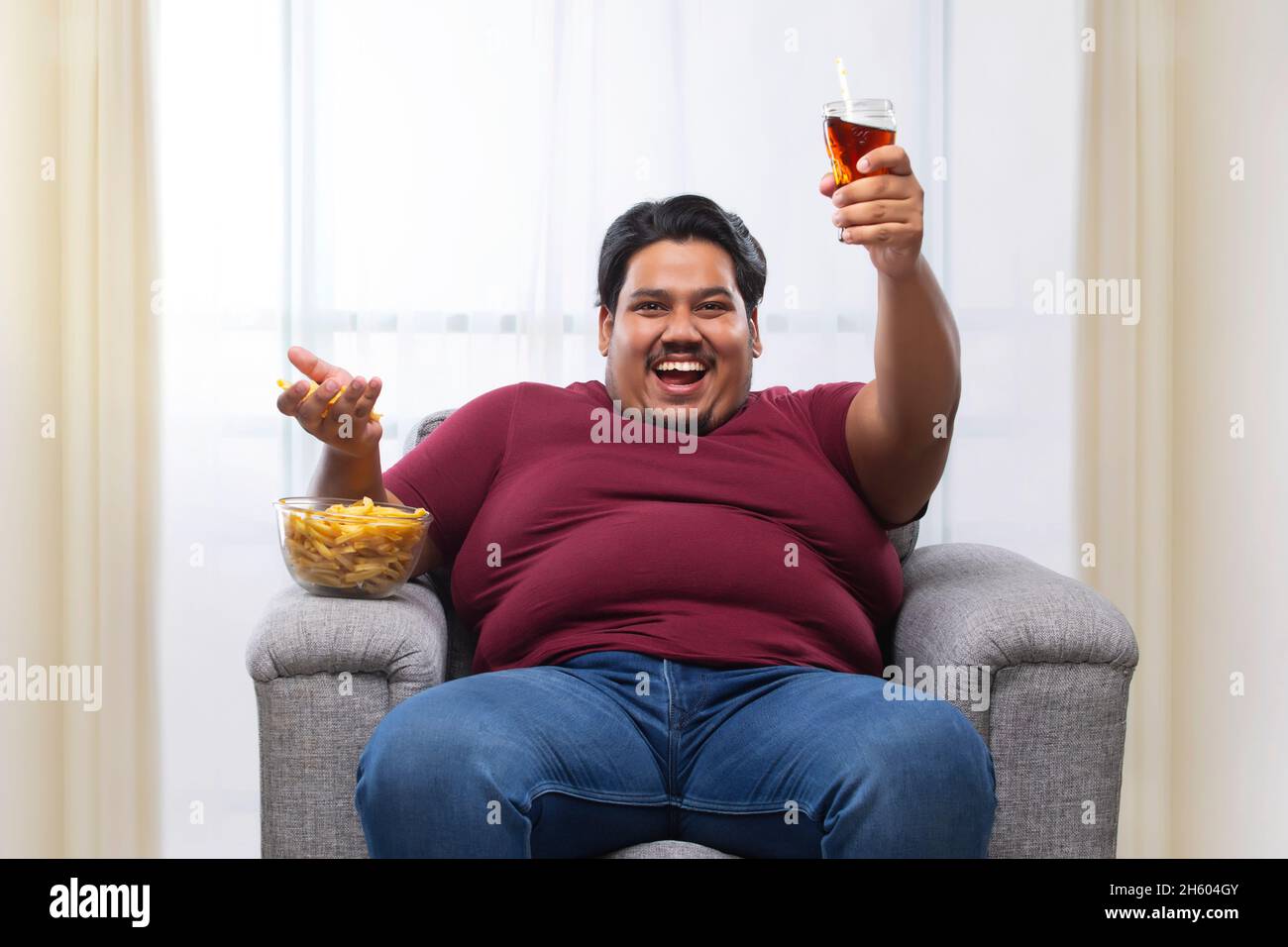 A fat man enjoying while sitting in his room with fries and cola in his ...
