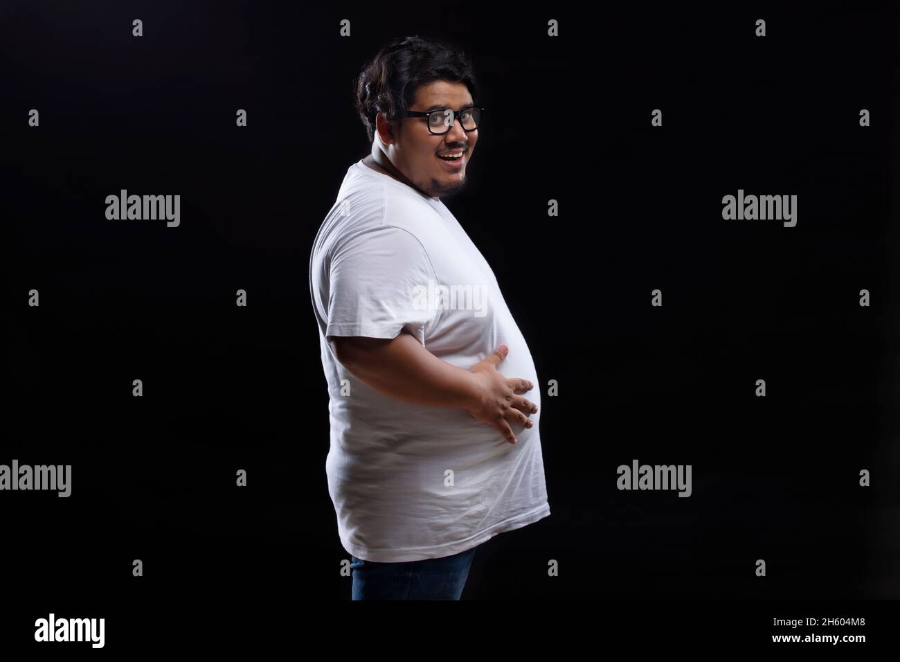 Portrait of a fat man smiling while placing hands on belly against ...