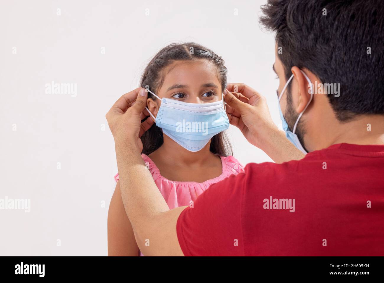 A FATHER PROTECTING DAUGHTER FROM PANDEMIC BY PUTTING FACE MASK Stock ...