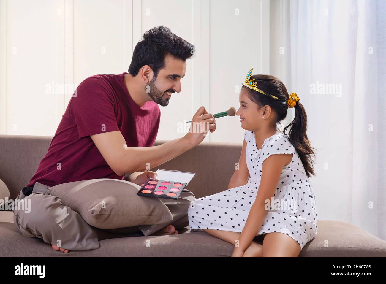 A FATHER HAPPILY PUTTING MAKEUP ON DAUGHTER WHILE PLAYING AT HOME Stock ...