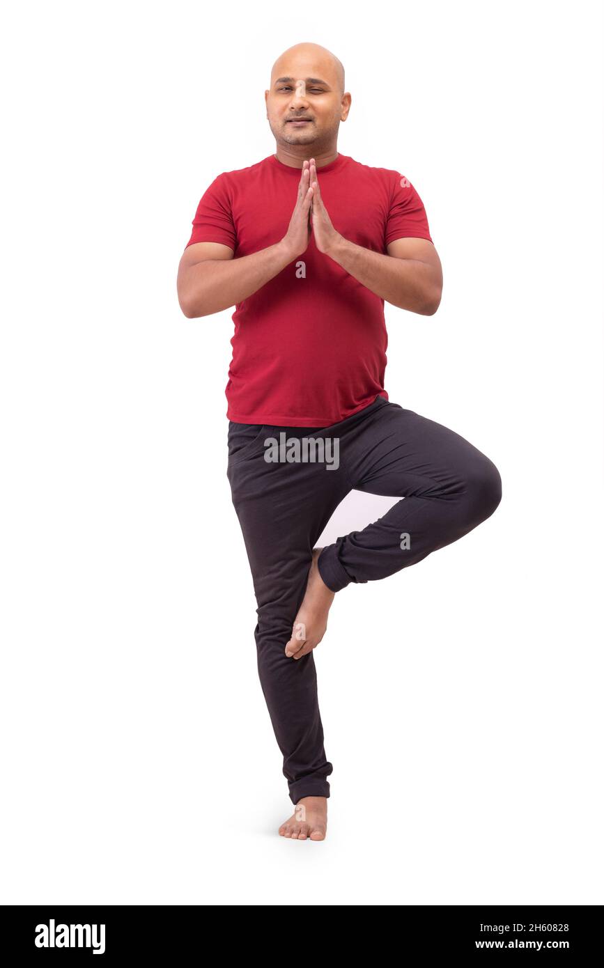 Portrait of a bald man standing and doing yoga against plain white ...