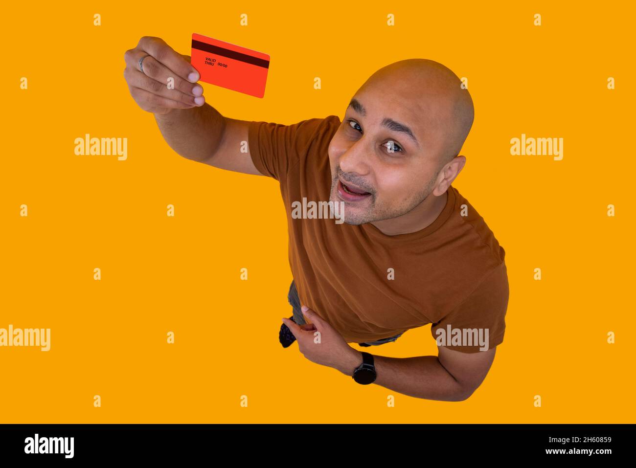 Portrait of a bald man showing the credit card in hand against plain ...