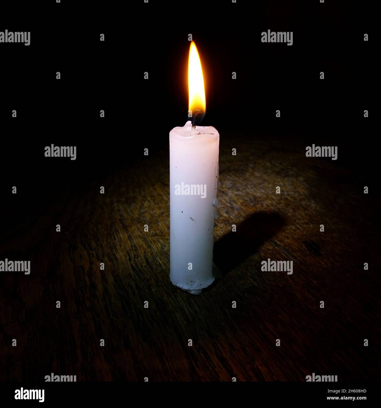 Burning candle and its shadow on square dark background Stock Photo - Alamy