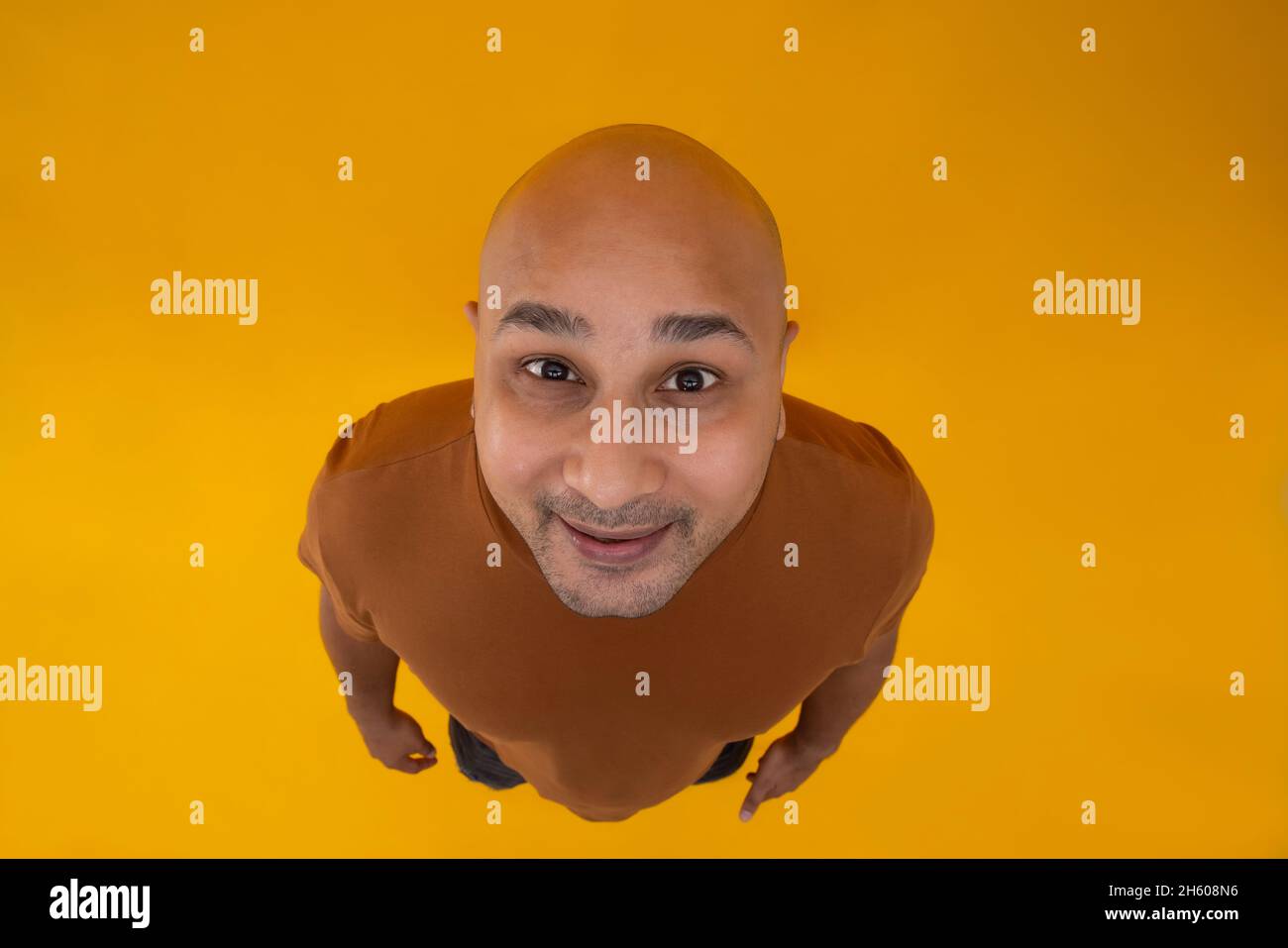 Portrait of a bald man standing and smiling against plain background ...