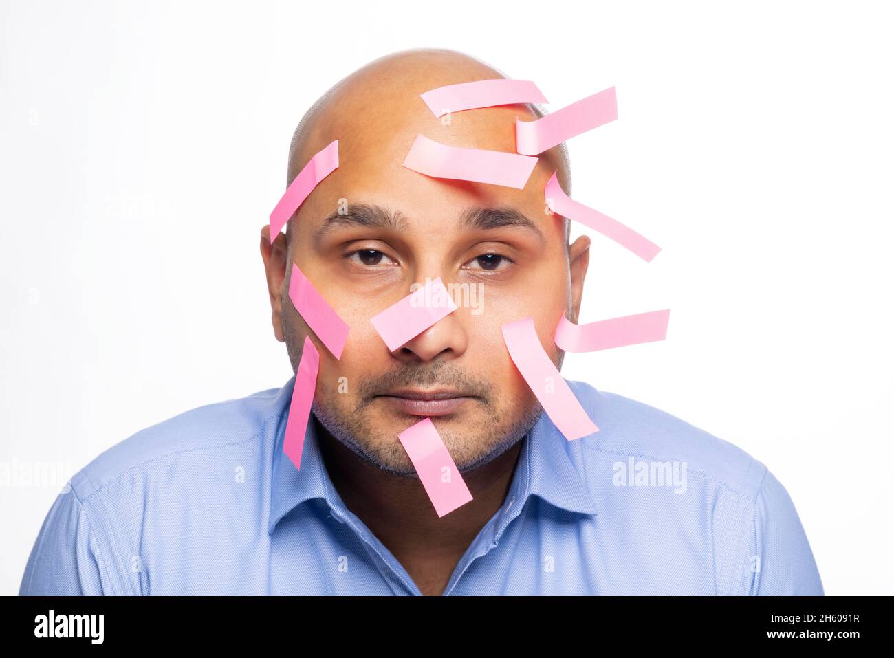 Portrait of a bald man with sticky notes on face against plain ...