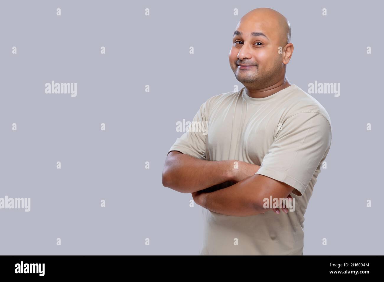Portrait of a bald man smiling with folded hands against plain ...