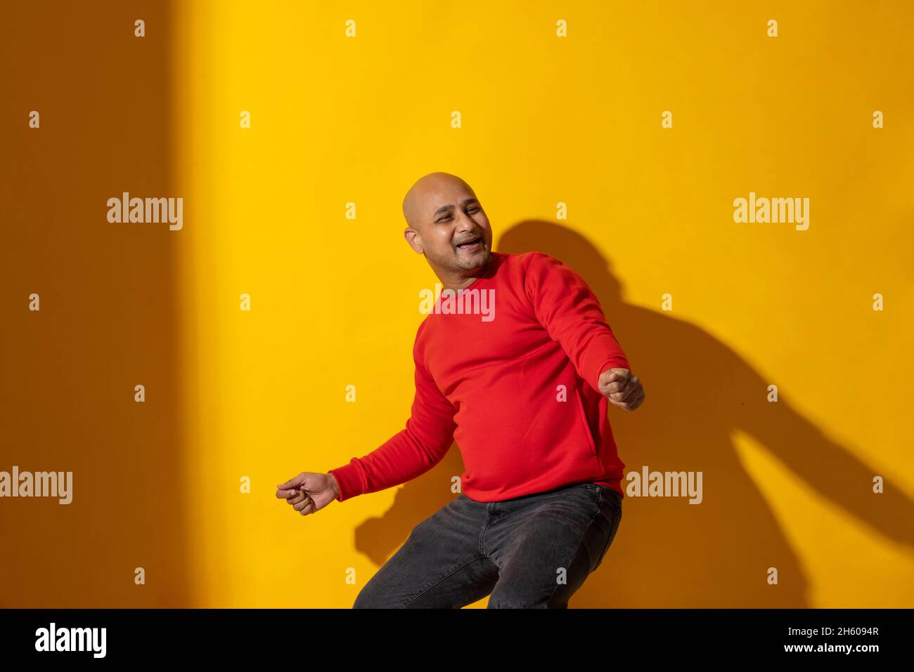 Portrait of a bald man dancing against plain background Stock Photo - Alamy