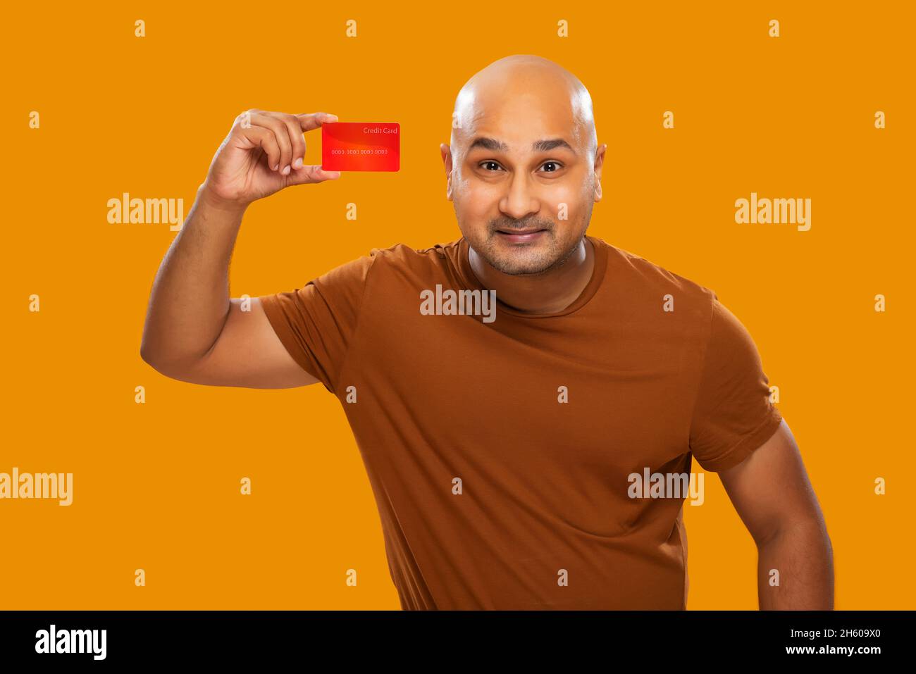 Portrait of a bald man showing the credit card in hand against plain ...
