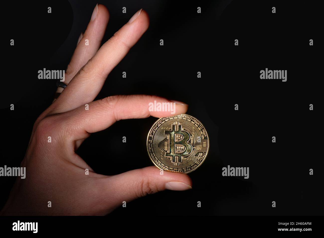 Crypto currency Bit Coin held between fingers on black background Stock ...