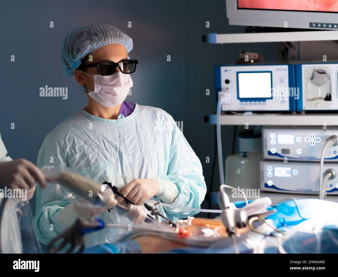 A female surgeon wearing 3D glasses operates on a patient. Laparoscopic ...