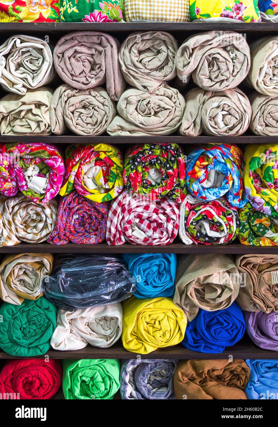 Vibrant colored fabrics rolled up on the shelves in the store Stock ...