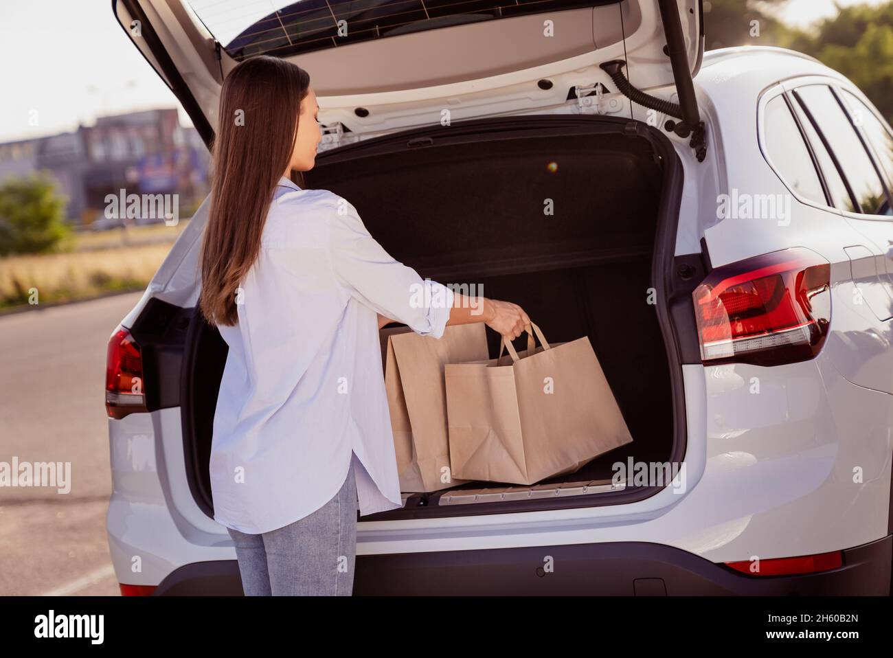 Photo of charming pretty young woman wear white shirt putting shopping ...