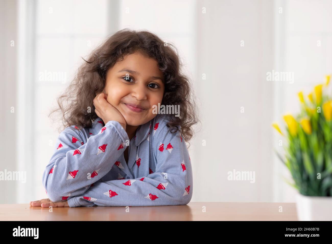 A beautiful girl posing in front of camera with right hand on cheek ...