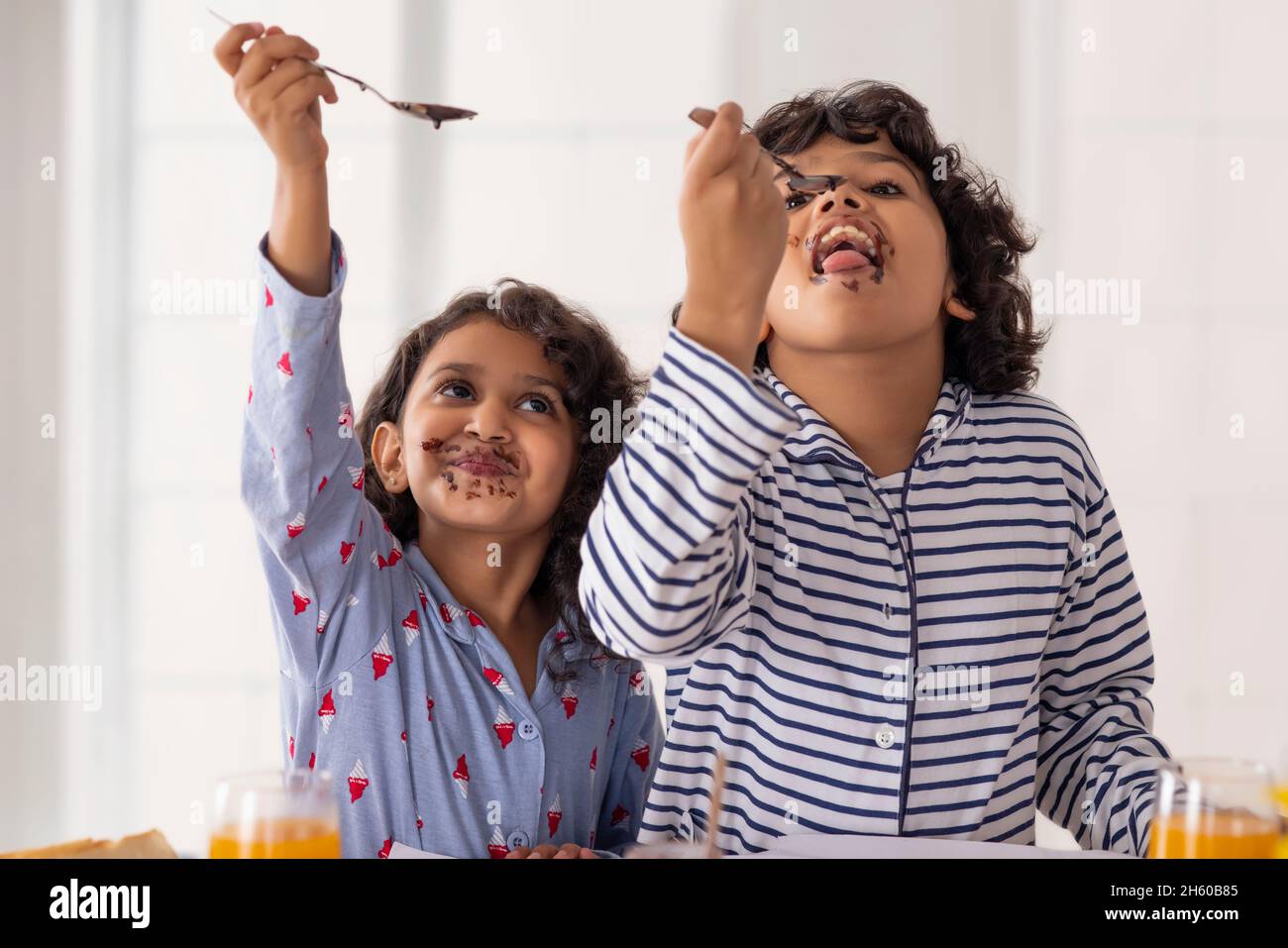Sibling having fun while eating chocolate with spoon Stock Photo - Alamy