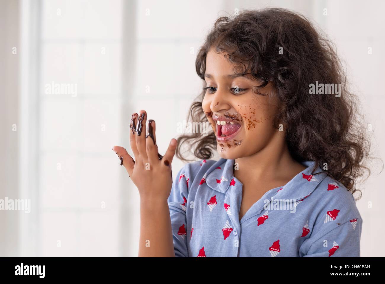 A girl having fun while eating chocolate with hand Stock Photo - Alamy