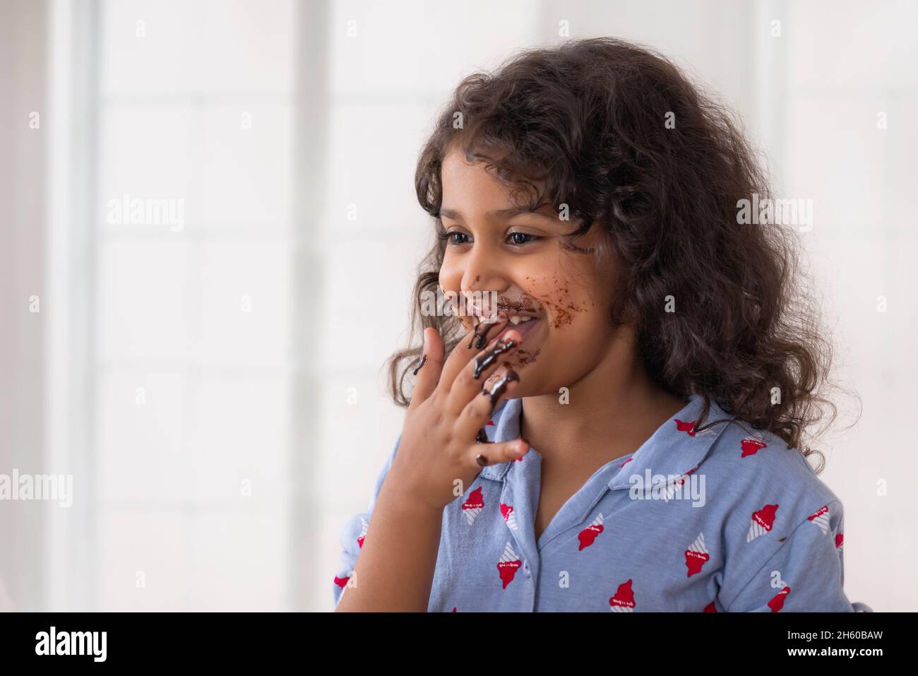 A girl having fun while eating chocolate with hand Stock Photo - Alamy