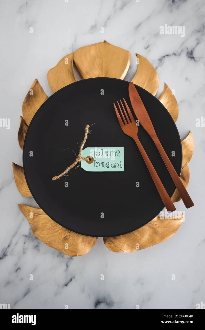 plant-based label on top of black dining plate with golden leaf ...