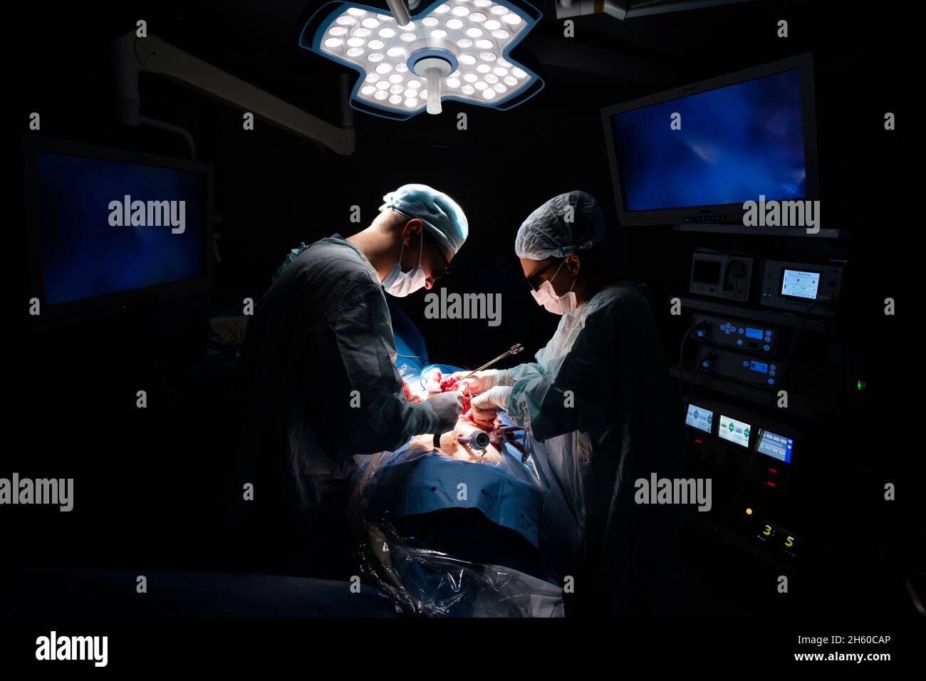 A team of surgeons wearing 3D glasses operate on a patient in the ...