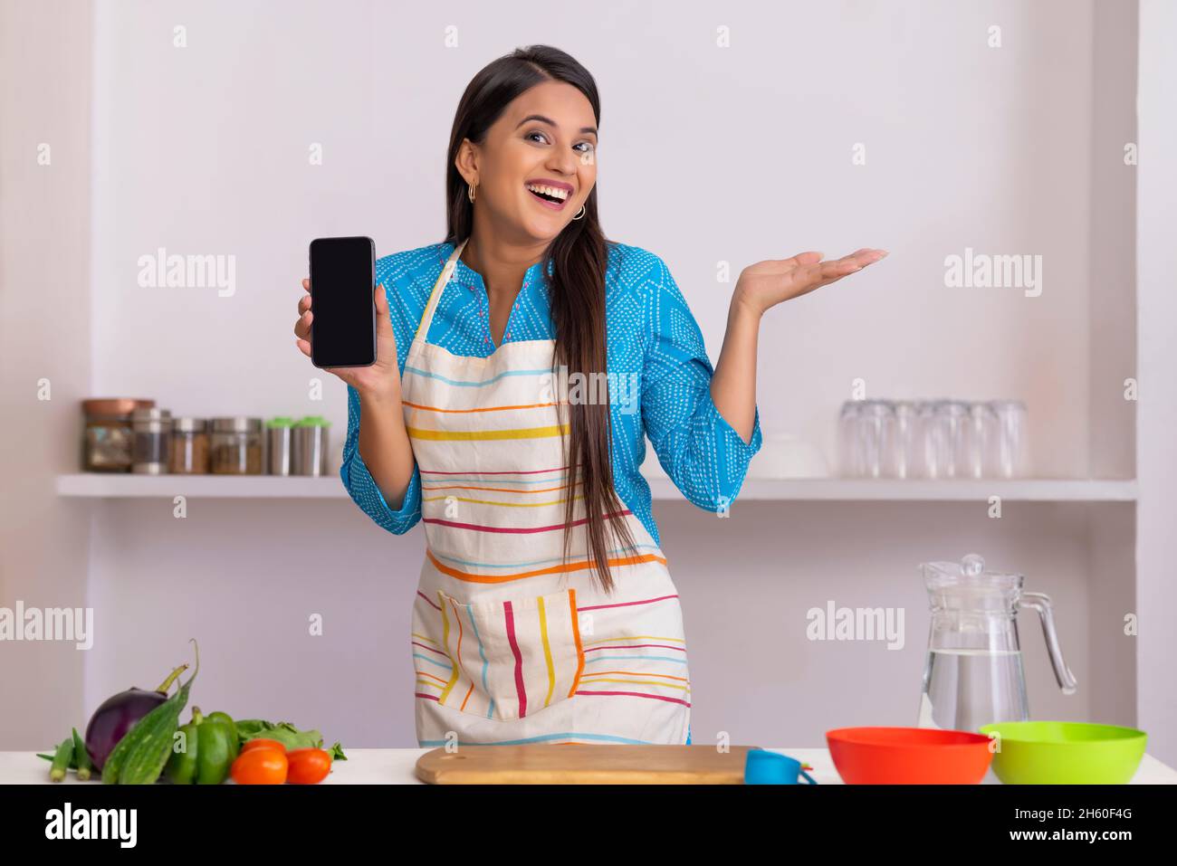Happy Indian lady posing with smartphone in Kitchen Stock Photo - Alamy