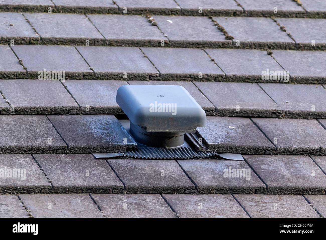 A close up portrait of a roof vent on a slate roof on a house. This ...