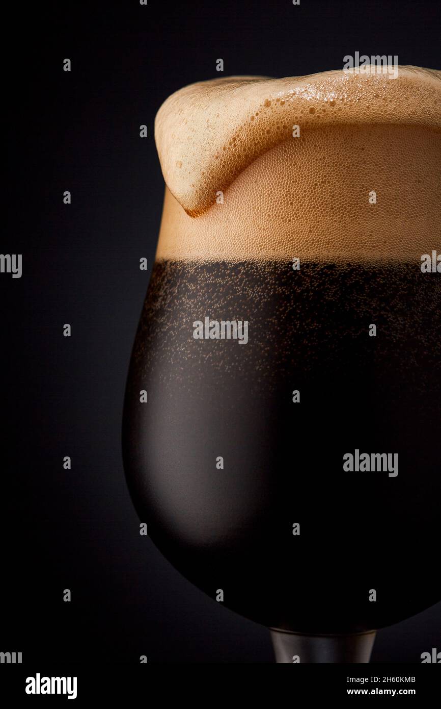 Close up of a glass of dark beer in a black background Stock Photo - Alamy