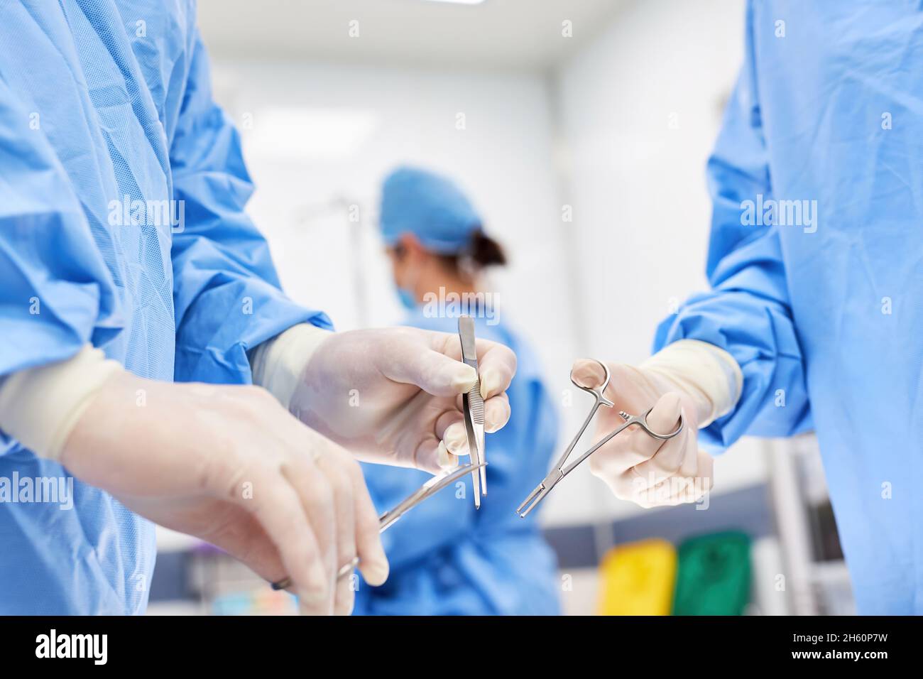 Surgeons wearing disposable gloves hold various instruments before ...