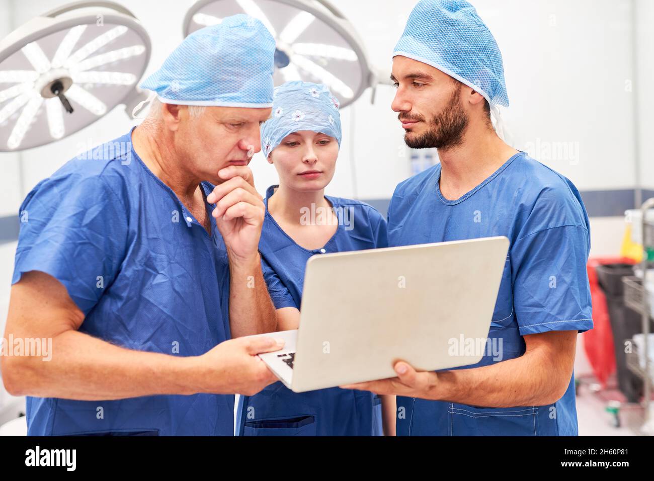 Surgery team looks at the laptop computer together during surgery ...
