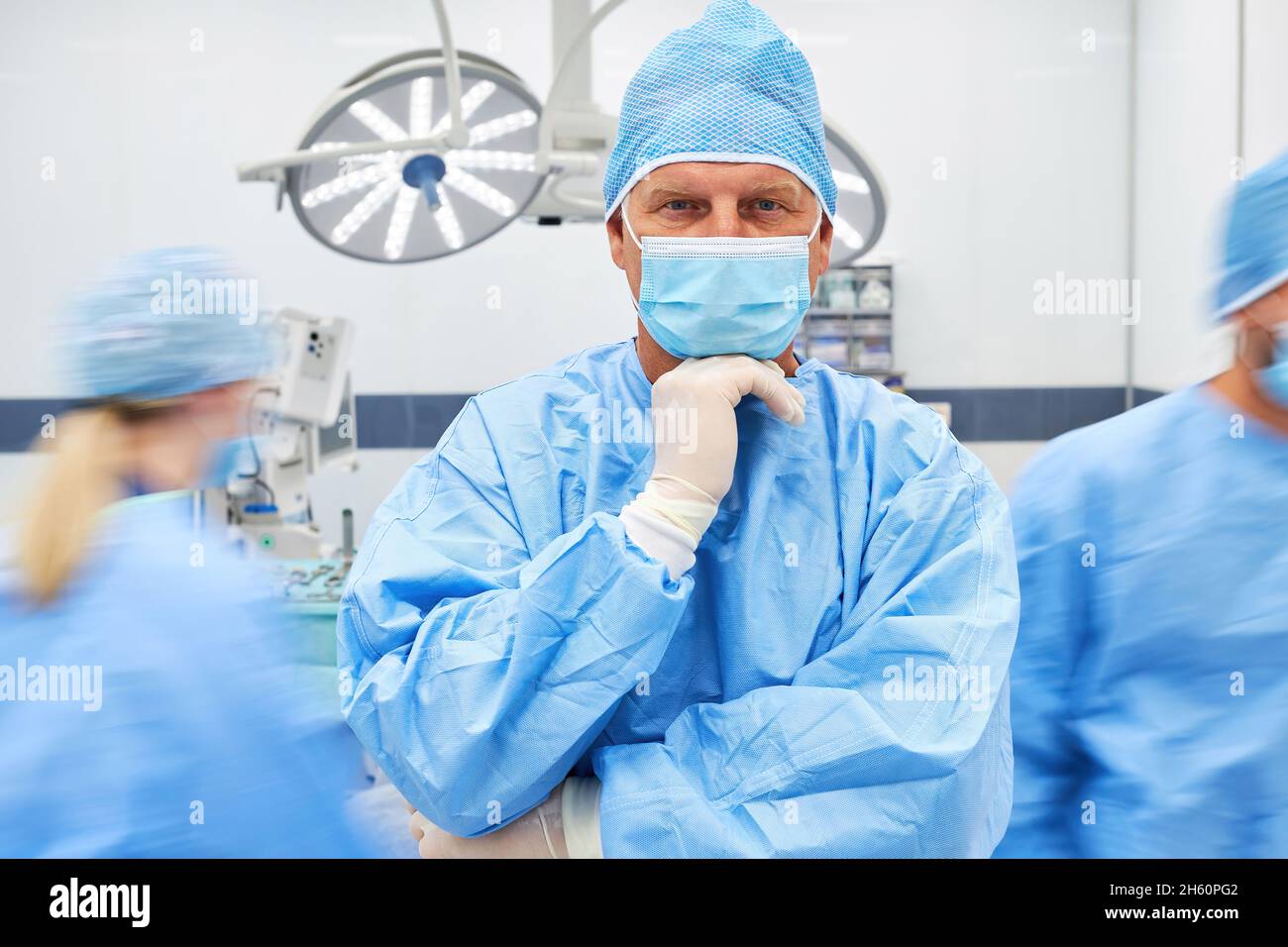 Portrait of surgeon in front of team in operating room with face mask ...
