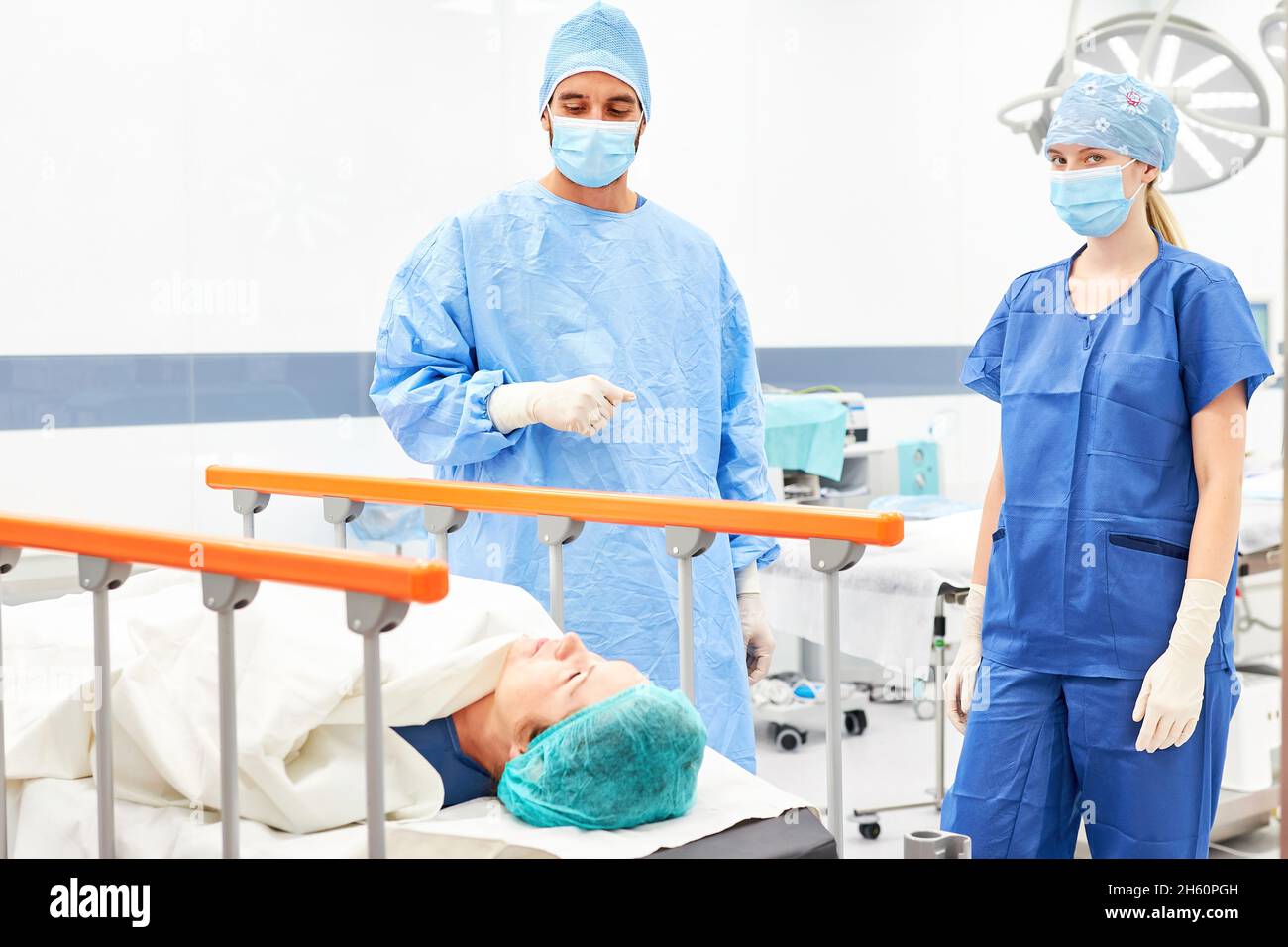Surgeon and operating room nurse talking to patient in hospital bed ...