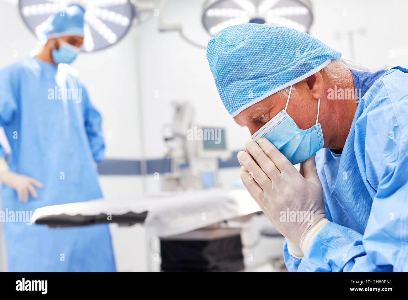 Elderly surgeon sits exhausted in the operating room after a strenuous ...